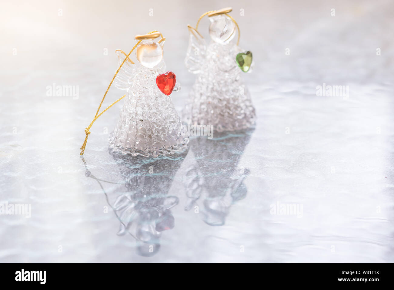 Two glass angels with hearts on the table Stock Photo - Alamy