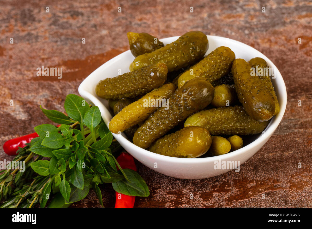 Pickled small cucumbers in the bowl served herbs Stock Photo - Alamy