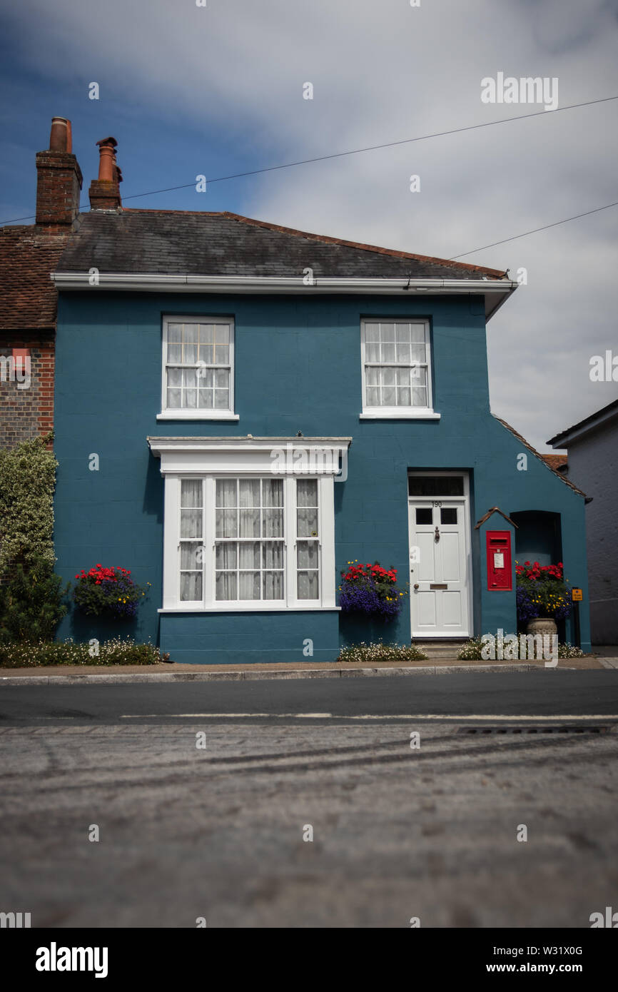 A blue old english cottage with a red post box in the wall Stock Photo ...