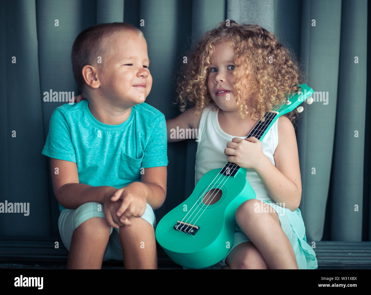Portrait of a cute kids sitting ouddoor with ukulele Stock Photo - Alamy