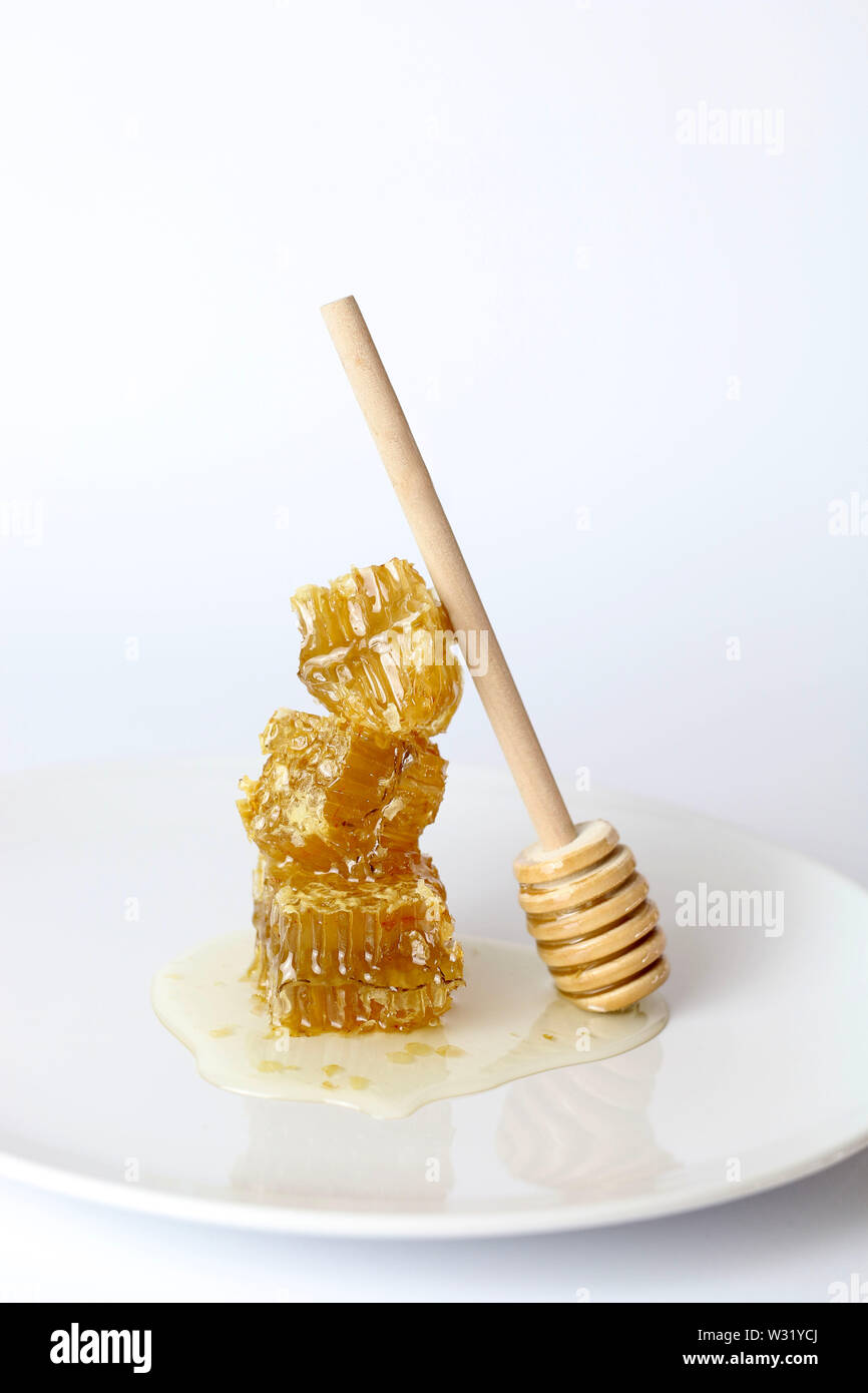 Closeup of honeycomb on a white plate with honey dipper isolated on ...