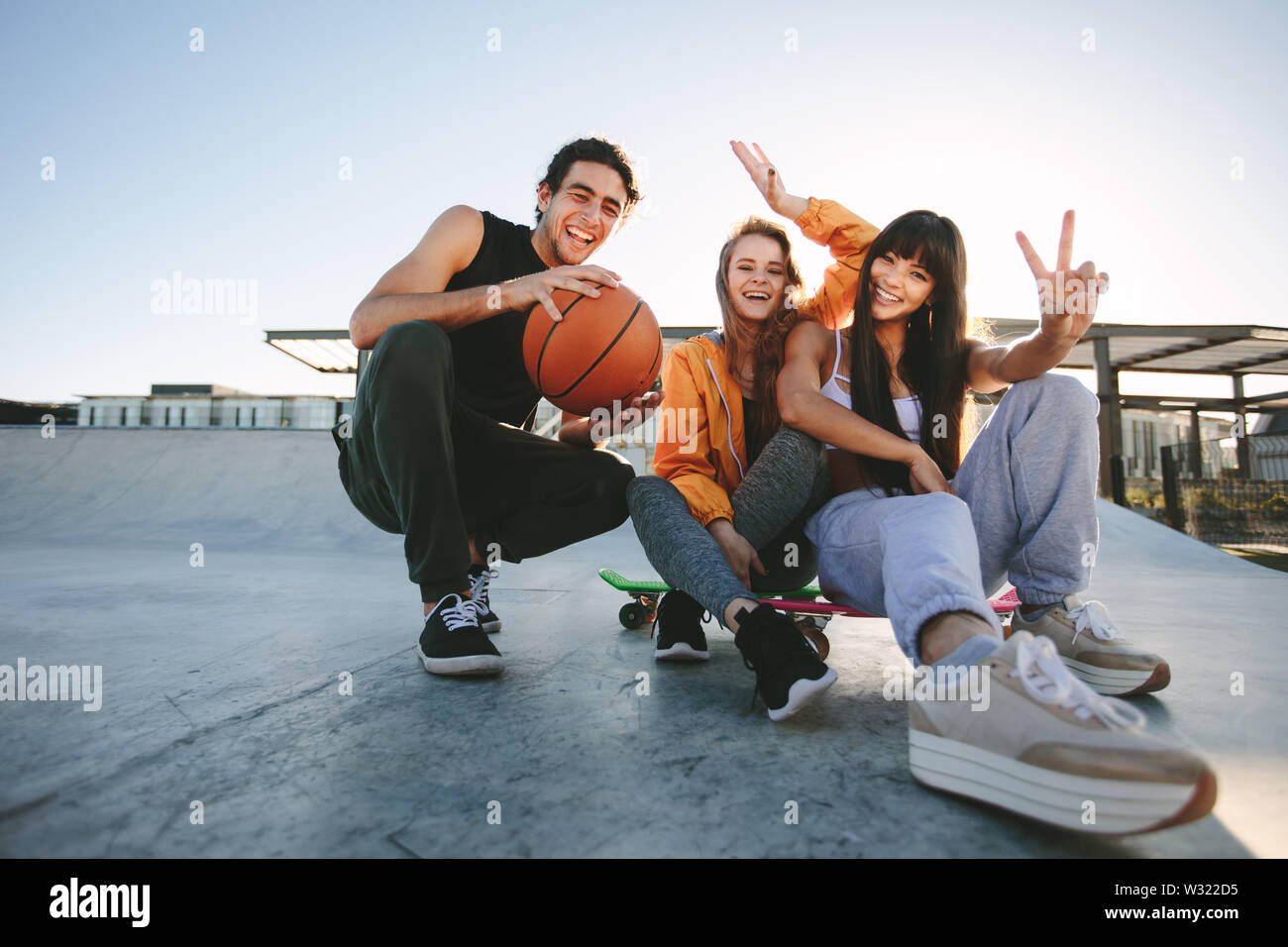 Group of friends sitting at skate park with skateboard and basketball ...