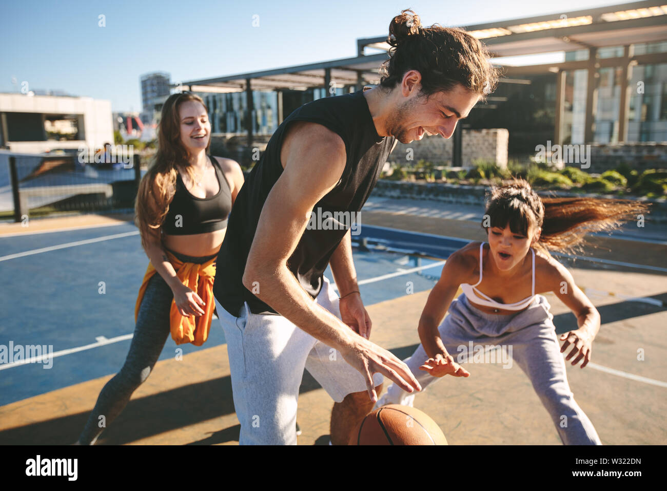 Friends playing basketball game on a sunny day on street court. Group ...