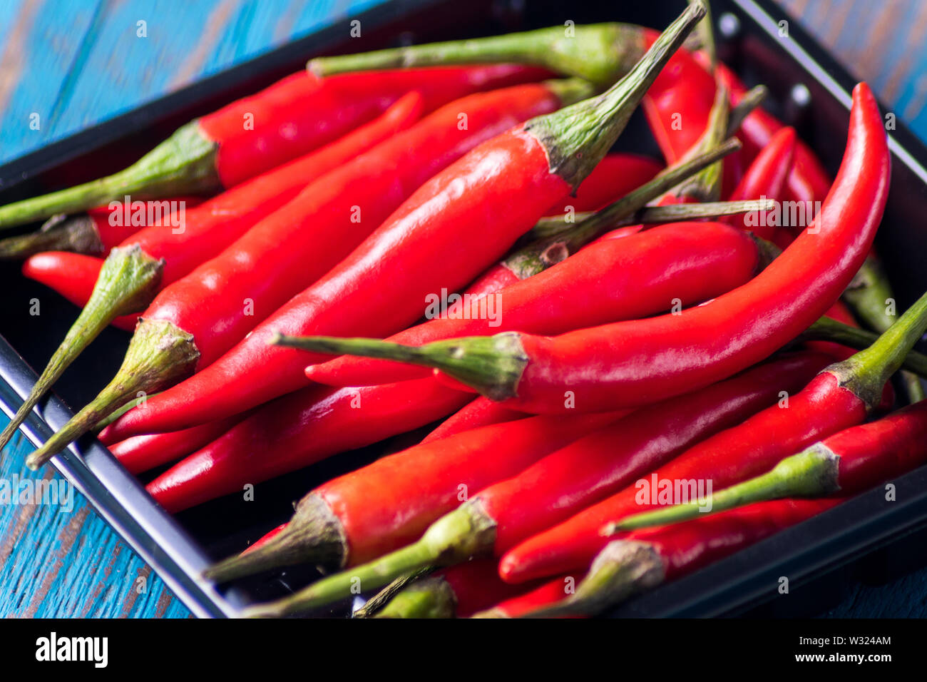 Top view Red ripe fresh chili peppers in in black plastic plate over ...