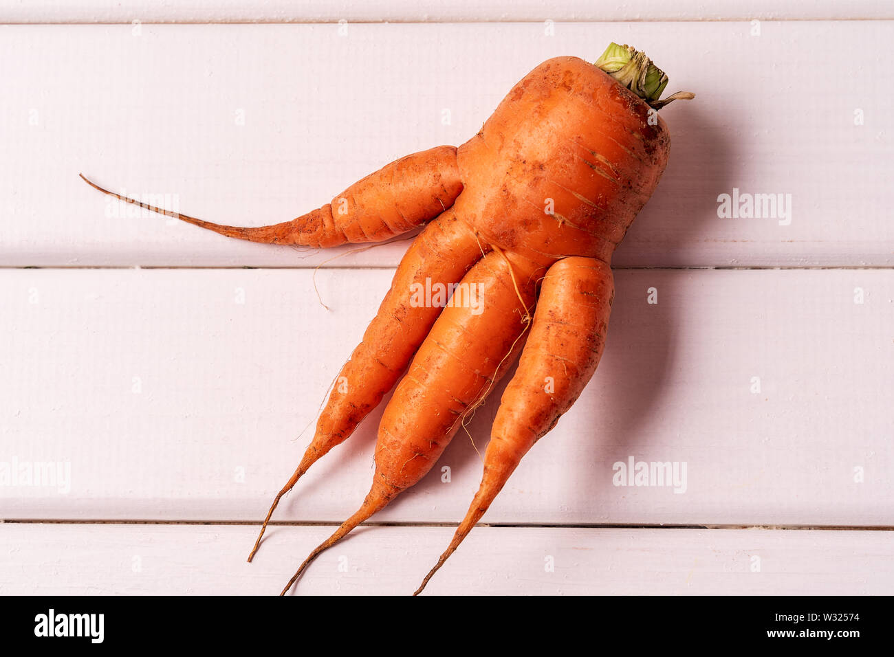 Flat lay Some ugly curved carrots on white wooden background Stock ...