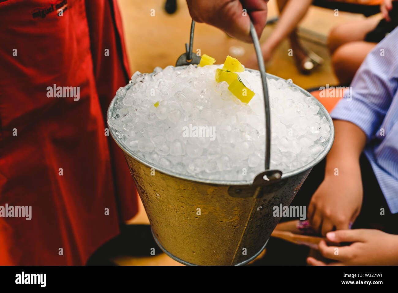 Waiter carrying a metal bucket full of ice to cool drinks in summer ...