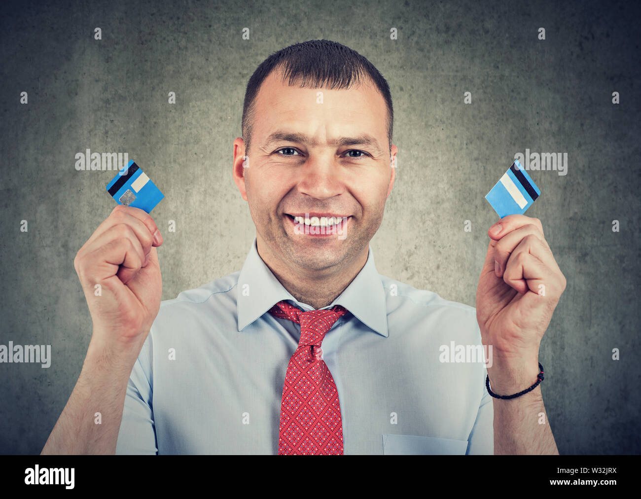 Happy debt free business man holding a credit card cut in two pieces ...