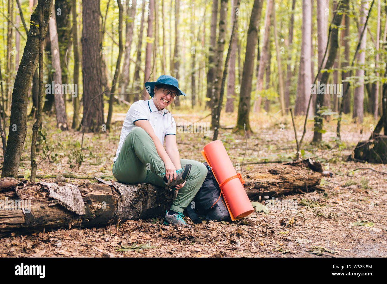 Young woman having trouble feeling knee pain during travel in forest ...