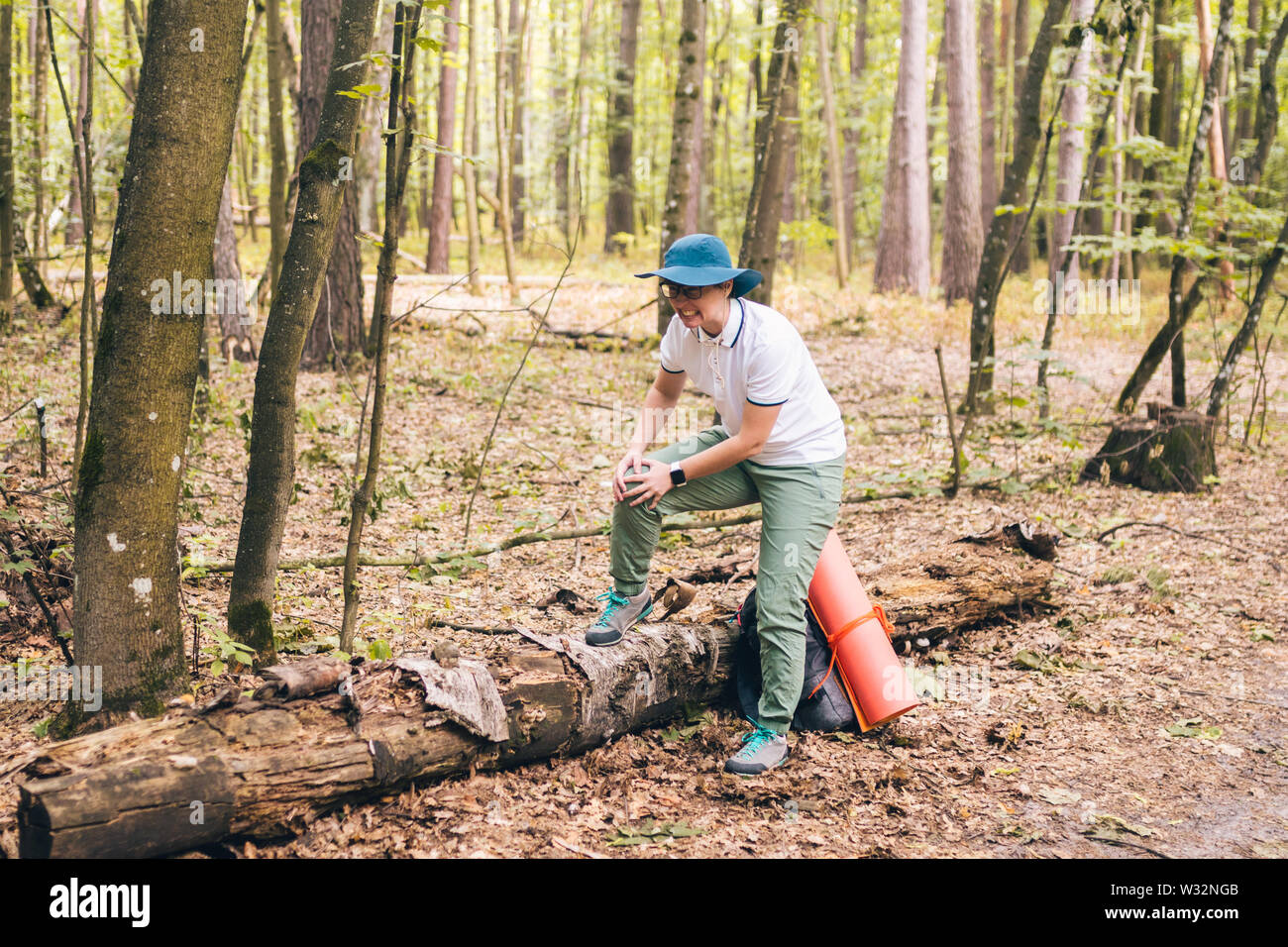 Young woman having trouble feeling knee pain during travel in forest ...