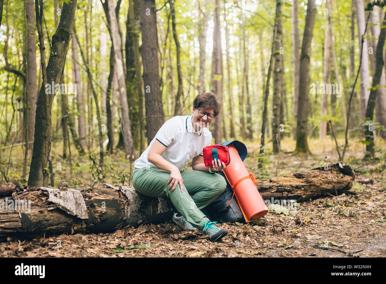 Young woman having trouble feeling knee pain during travel in forest ...