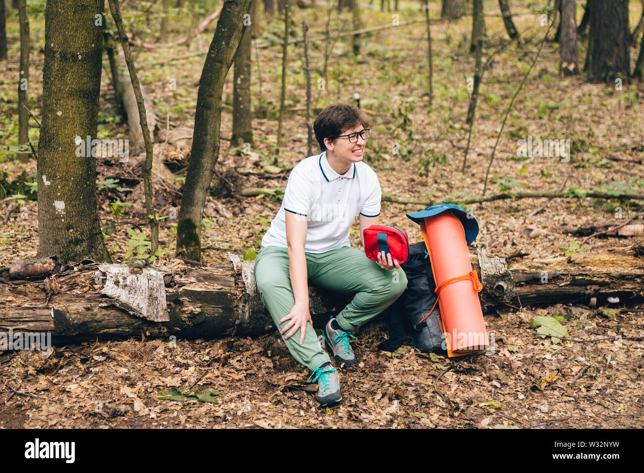 Young woman having trouble feeling knee pain during travel in forest ...