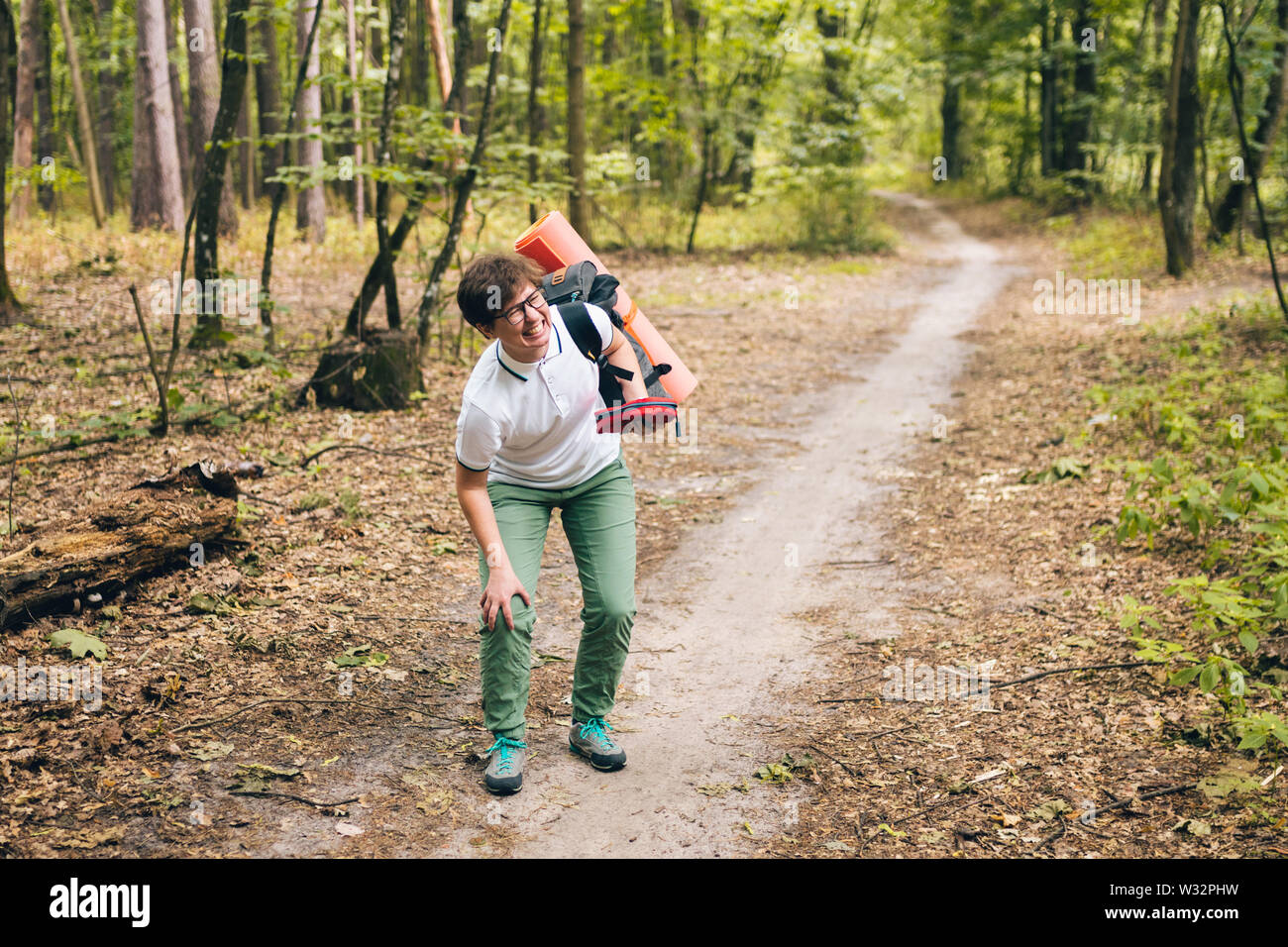 Young woman having trouble feeling knee pain during travel in forest ...