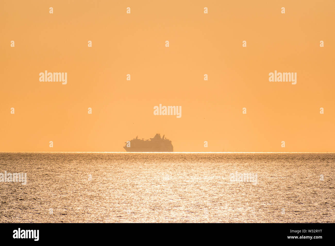 A cruise ship sailing over the horizon during sunset Stock Photo - Alamy