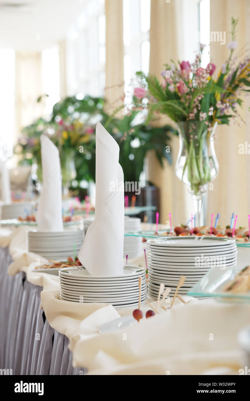 Table with dishware and tasty food waiting for guests Stock Photo - Alamy