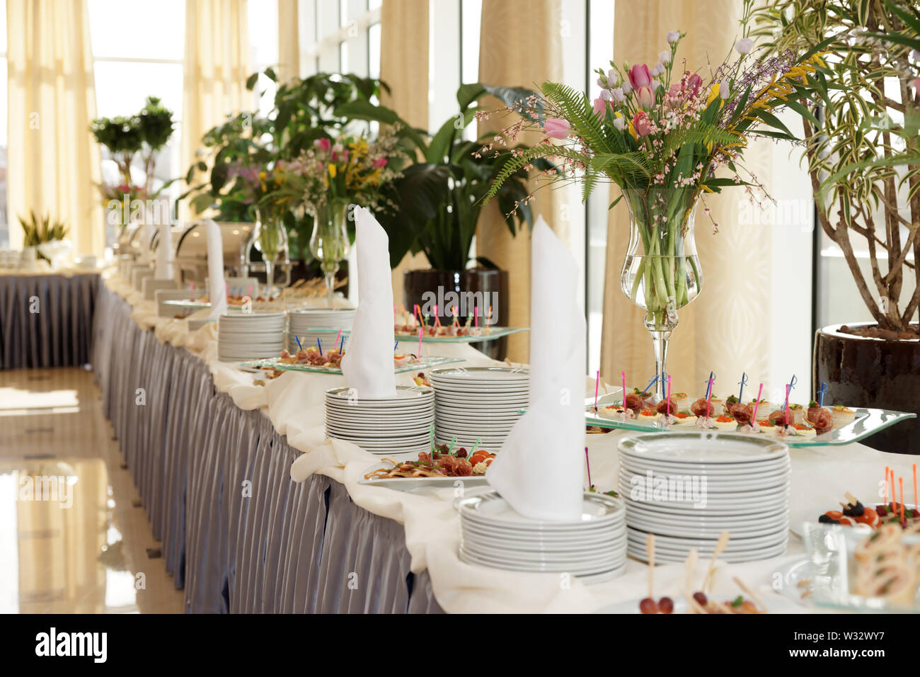 Table with dishware and tasty food waiting for guests Stock Photo - Alamy