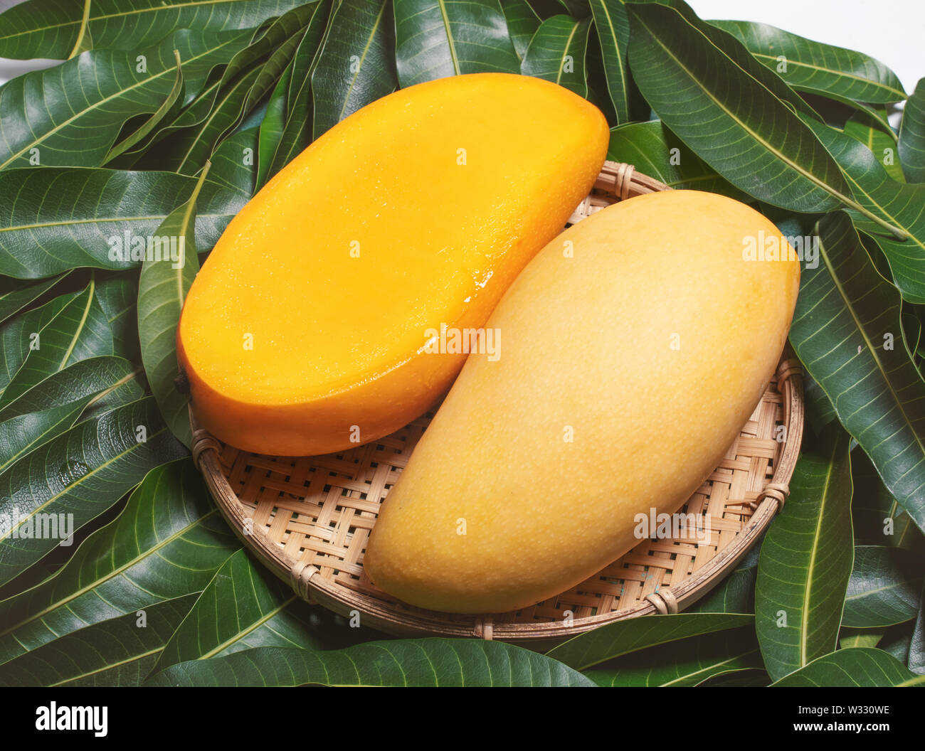 Fresh Mango - Juicy diced fruit in bamboo sieve on green color leaves ...