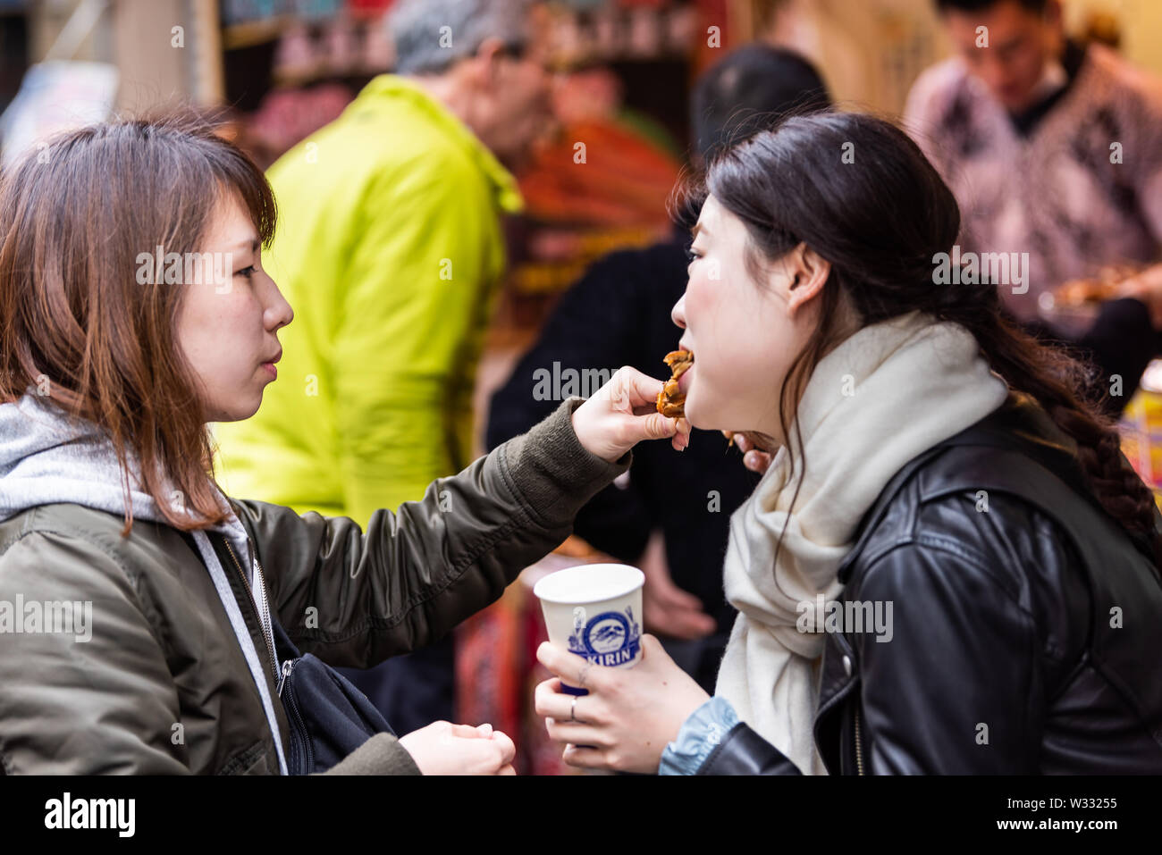 Tokyo, Japan - March 30, 2019: Two Chinese Asian women friends feeding ...