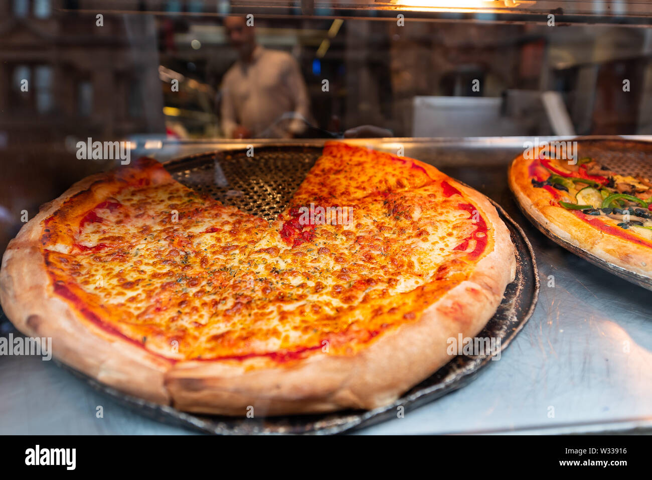 Closeup of fresh large crust pizza in store cafe on display restaurant ...