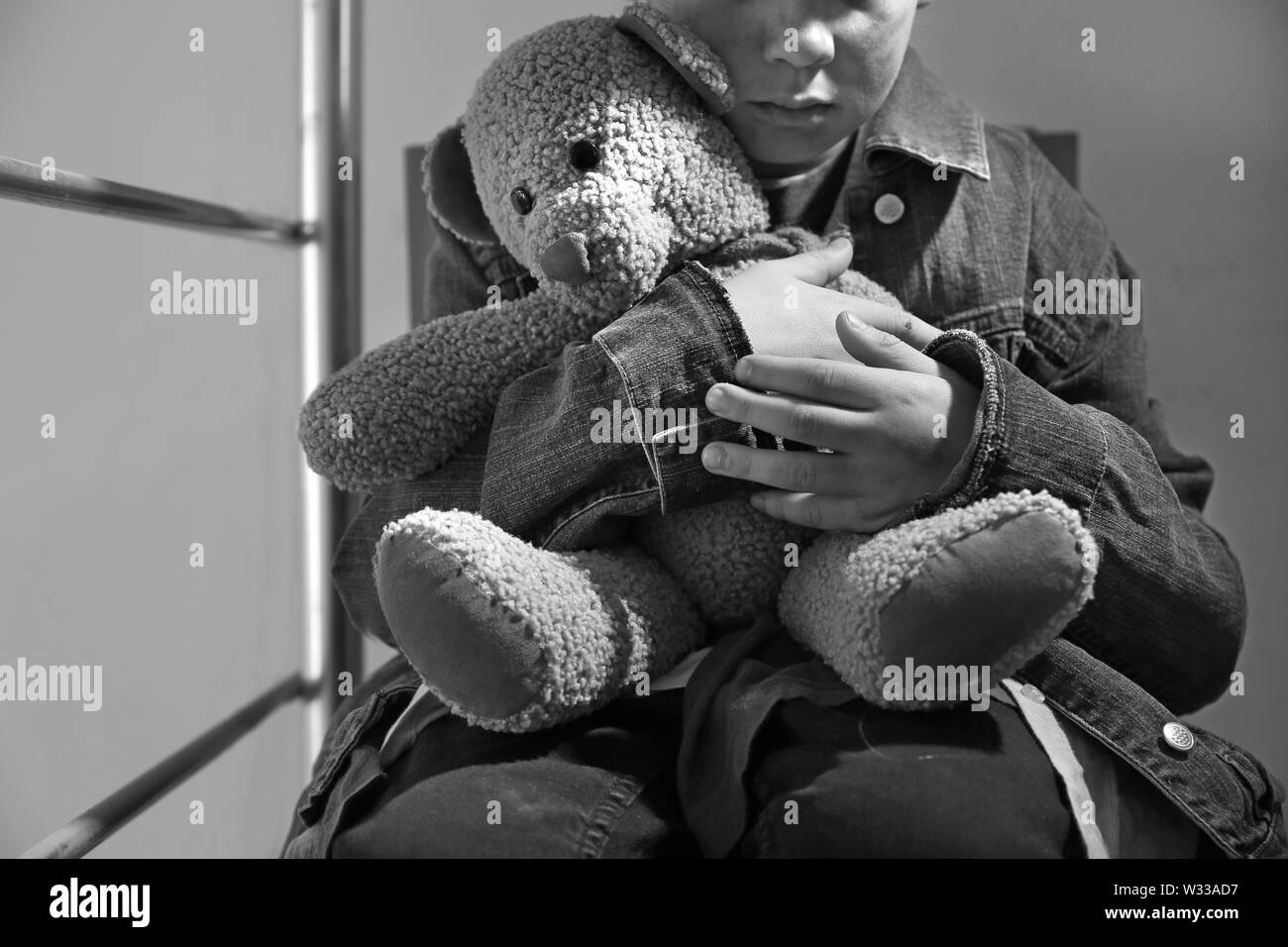 Homeless little boy with teddy bear sitting indoors Stock Photo - Alamy