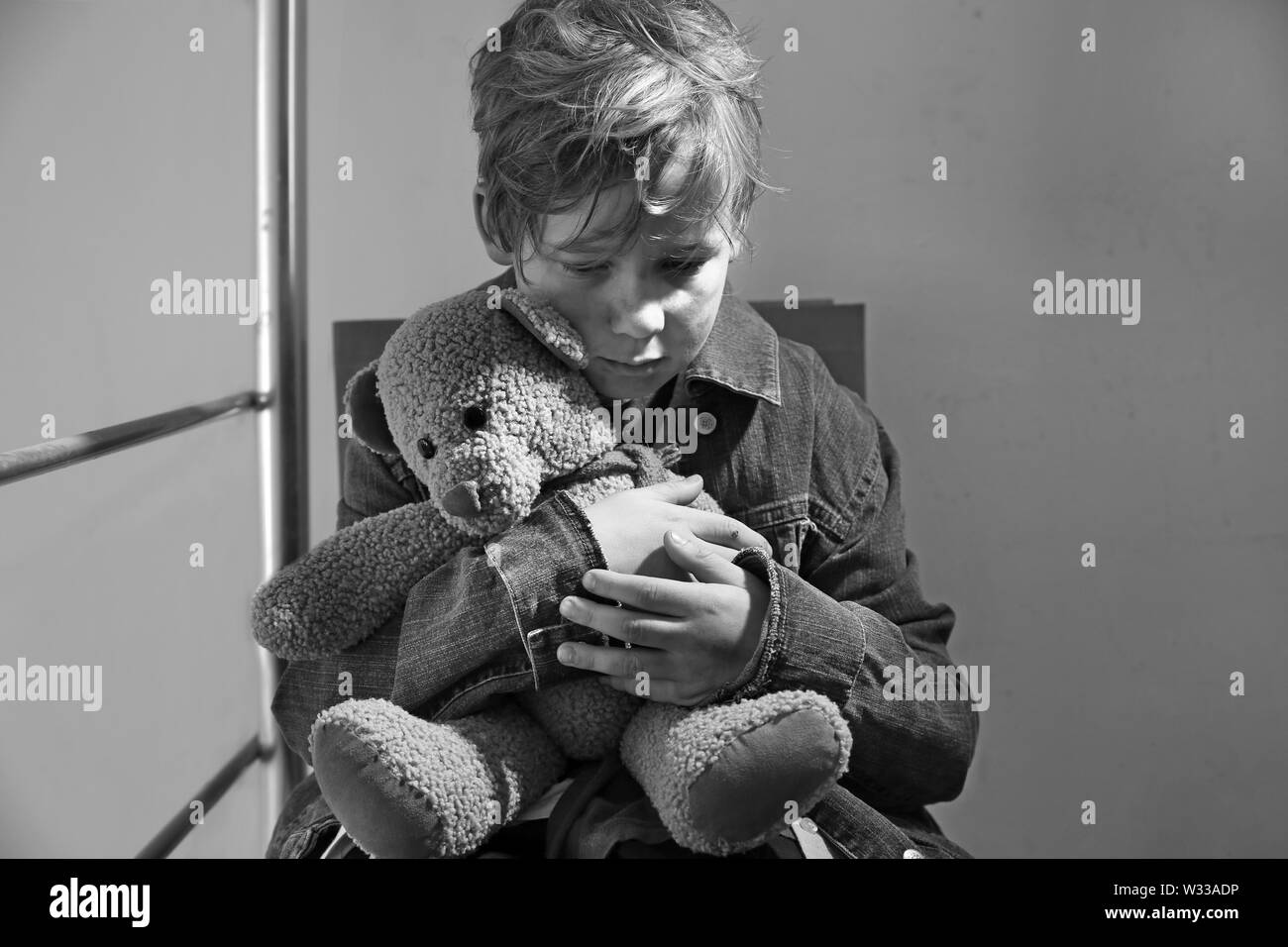 Homeless little boy with teddy bear sitting indoors Stock Photo - Alamy