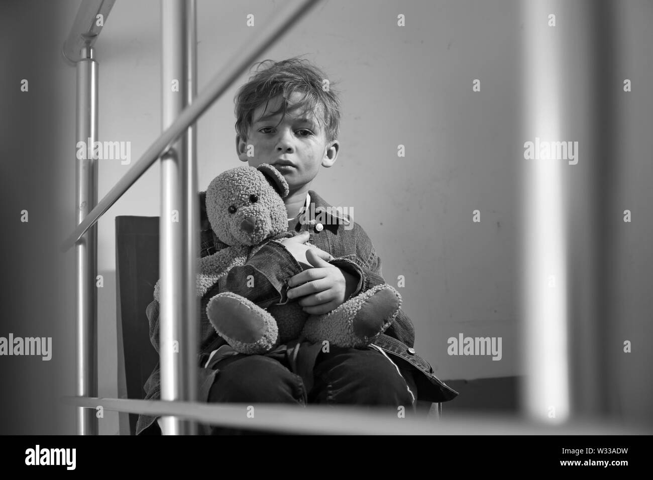 Homeless little boy with teddy bear sitting indoors Stock Photo - Alamy