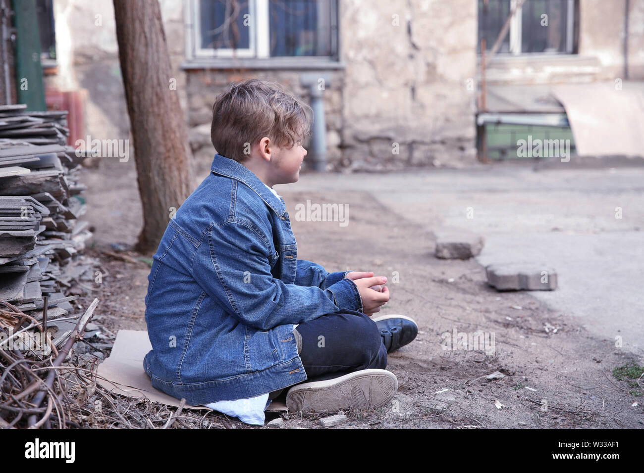 Homeless little boy sitting outdoors Stock Photo - Alamy