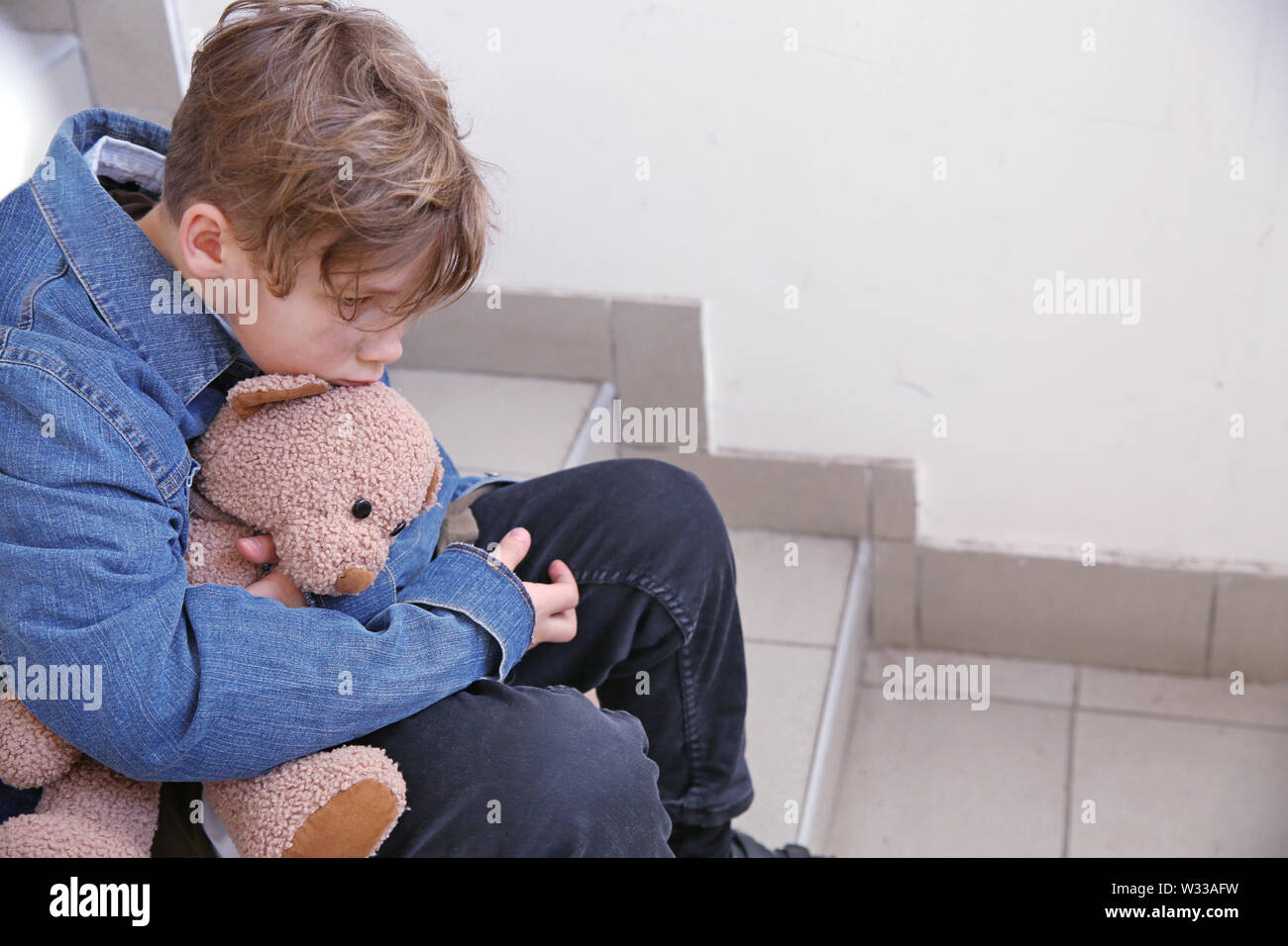 Homeless little boy with teddy bear sitting on steps Stock Photo - Alamy