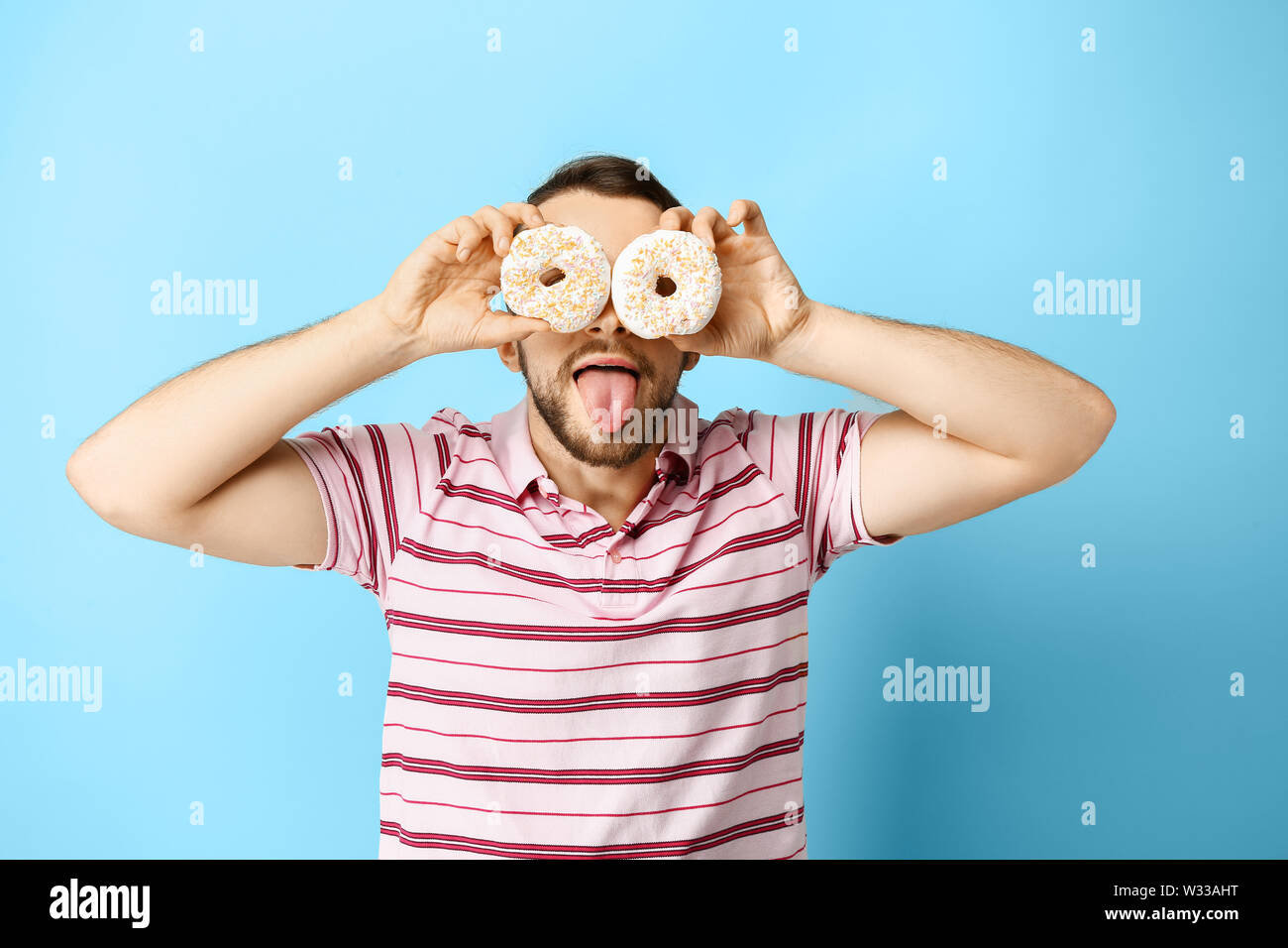 Funny man with donuts on color background Stock Photo - Alamy