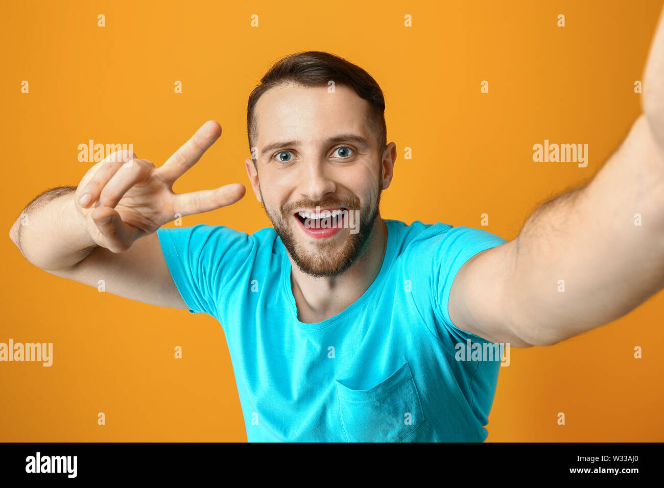 Handsome man taking selfie on color background Stock Photo - Alamy