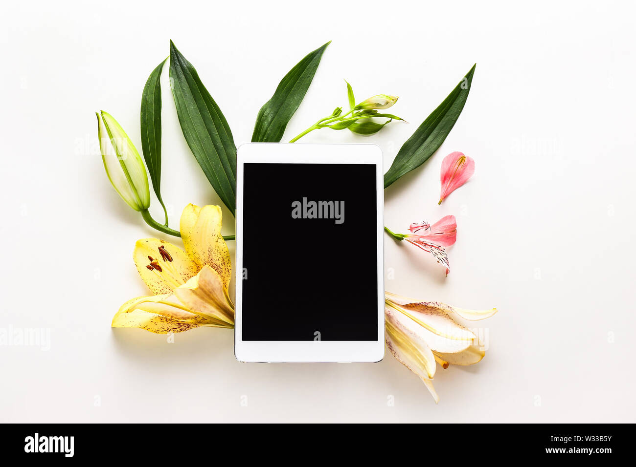 Tablet computer, flowers and leaves on white background Stock Photo - Alamy