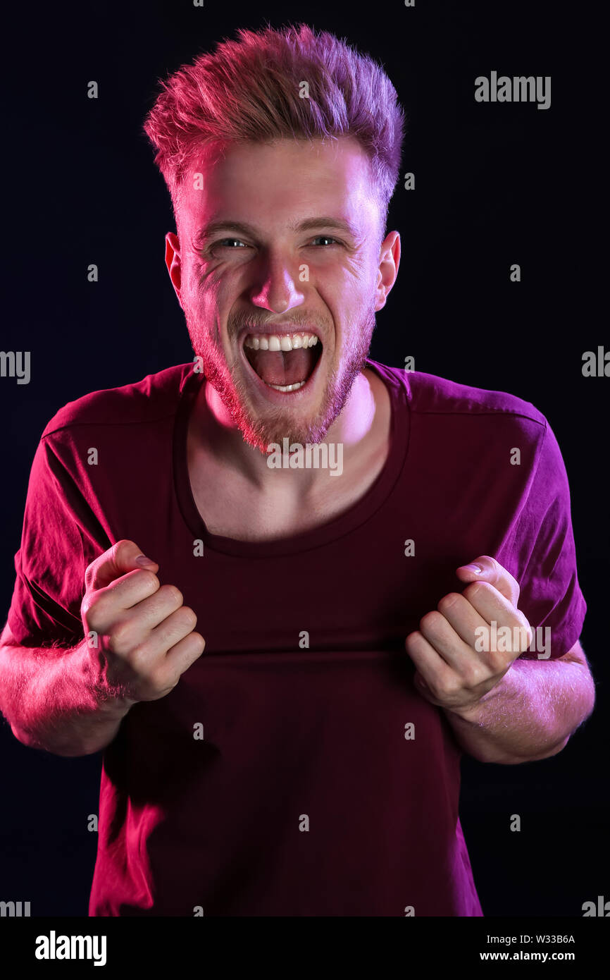 Aggressive young man on dark background Stock Photo - Alamy