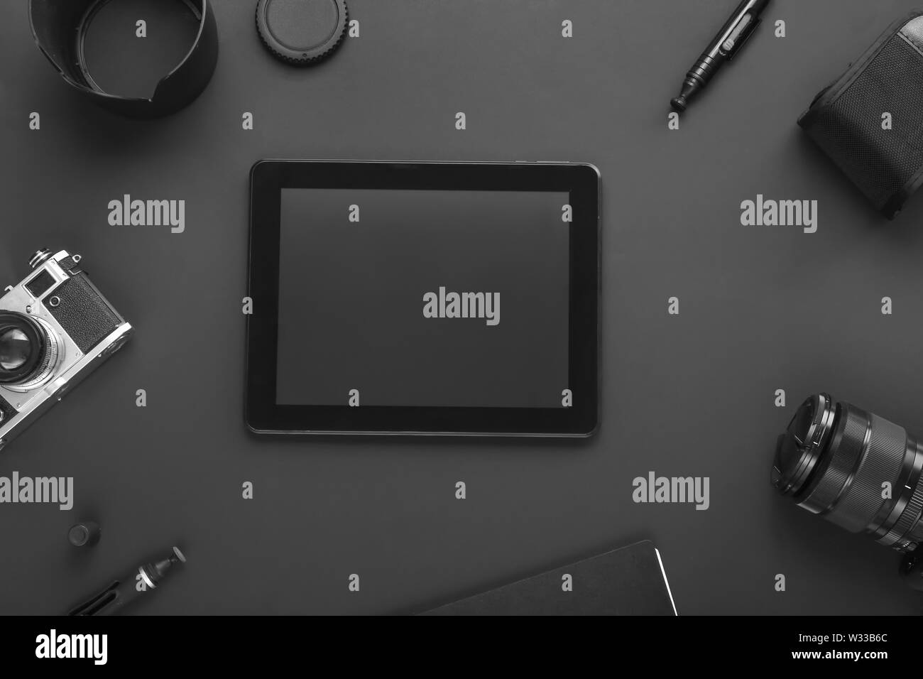 Tablet computer and set of photographer's equipment on dark background ...