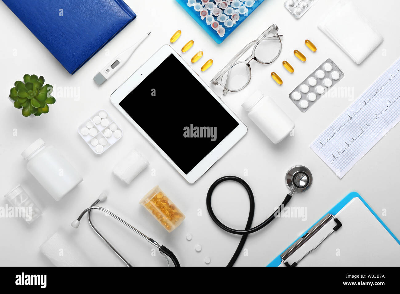 Tablet computer, pills, stethoscope and notebook on white background ...
