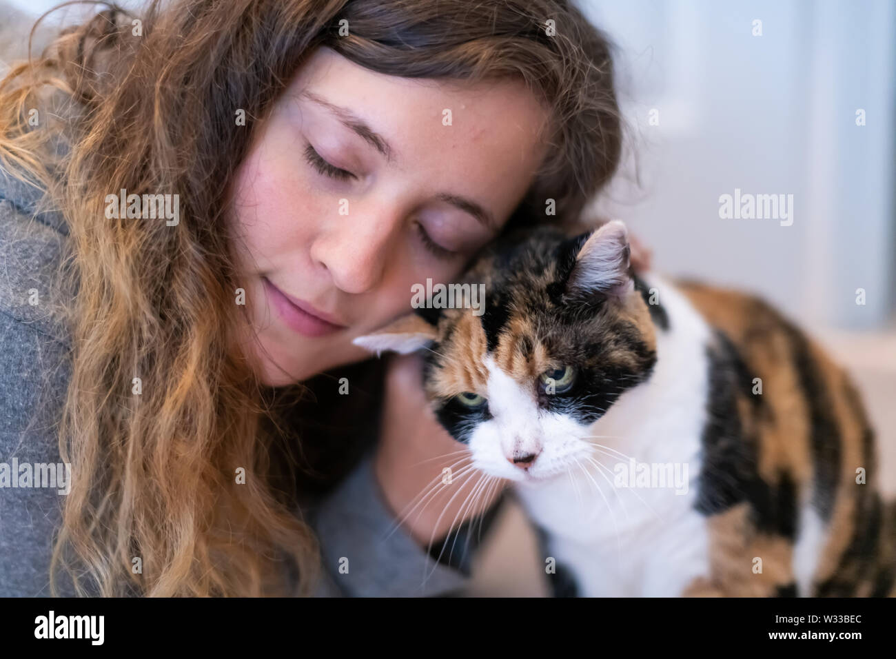Closeup portrait of happy smiling young woman bonding with calico cat ...