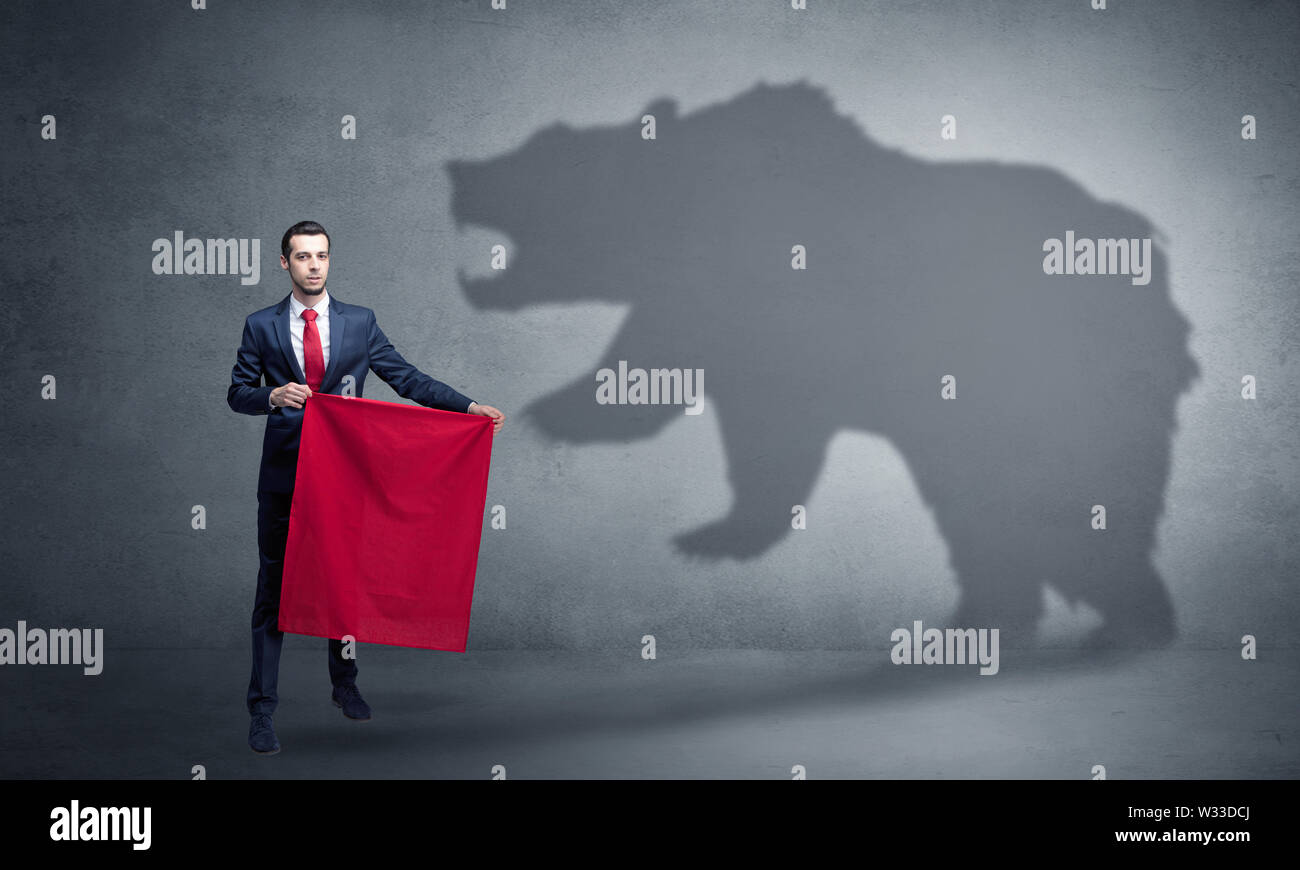 Businessman standing with red cloth in his hand and big bear shadow on ...