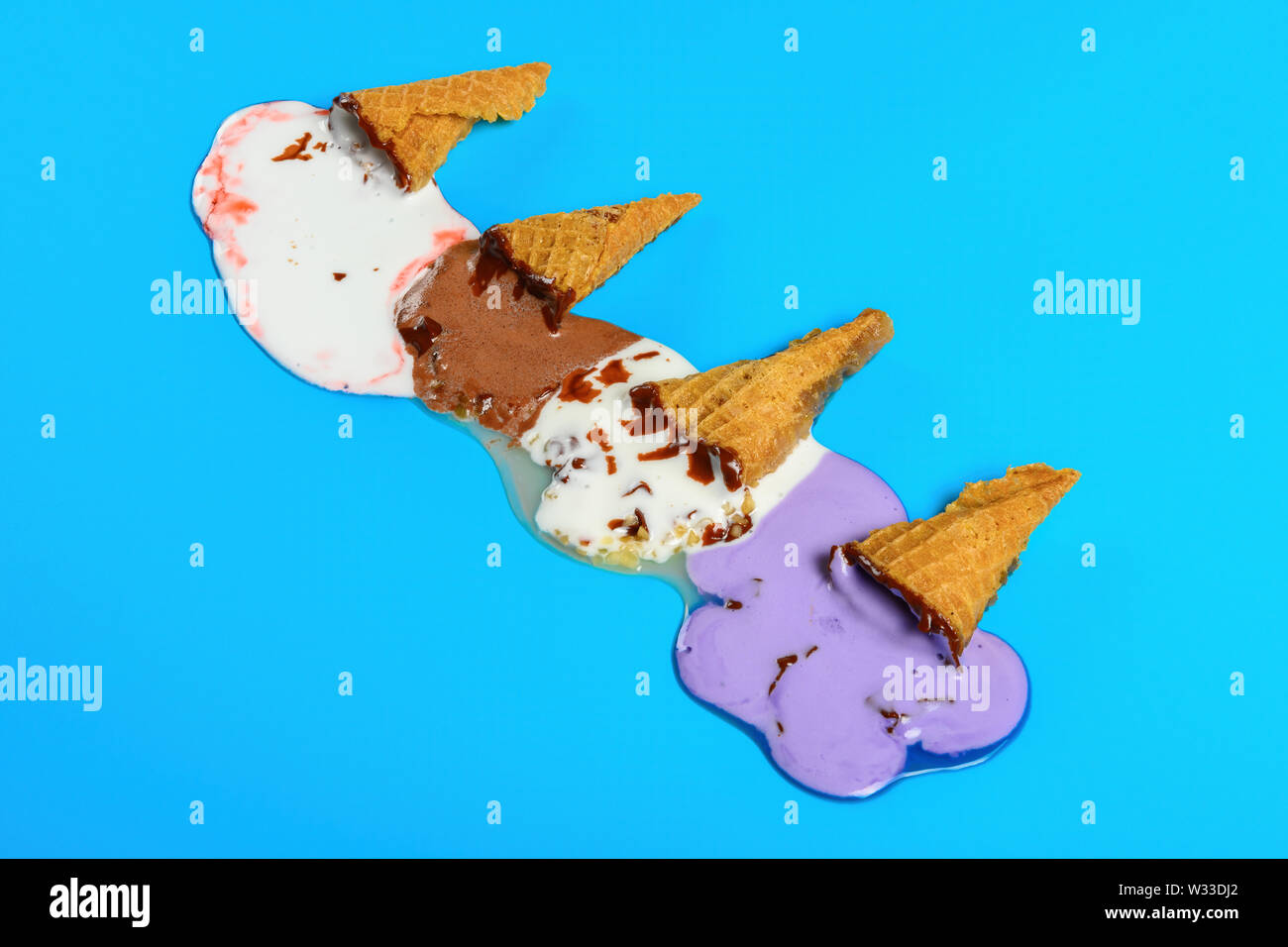 angle view multiple flavor ice cream cones melted on blue background ...