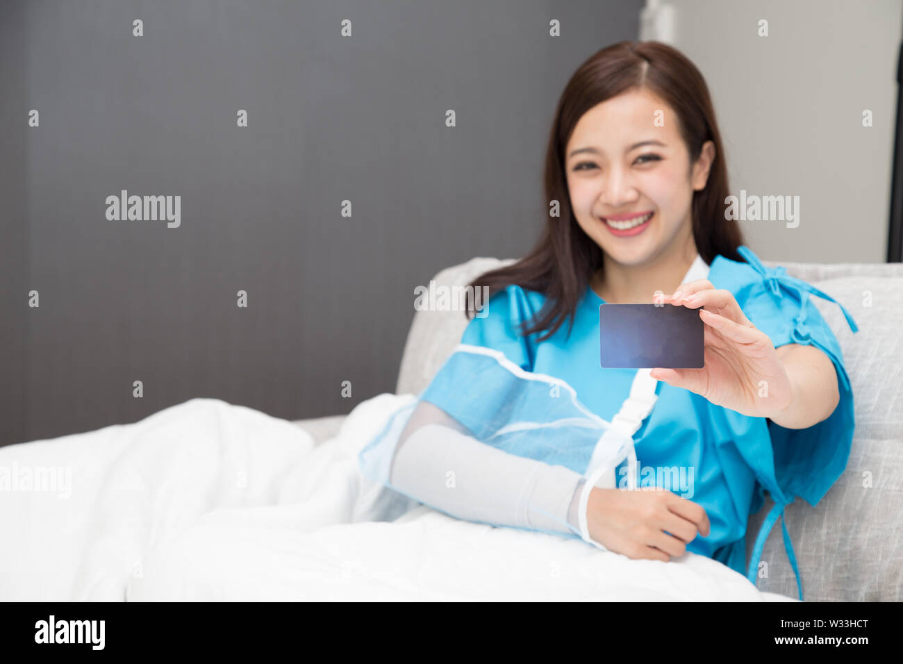 Asian woman holding insurance cards and wear patient suits on the arms ...