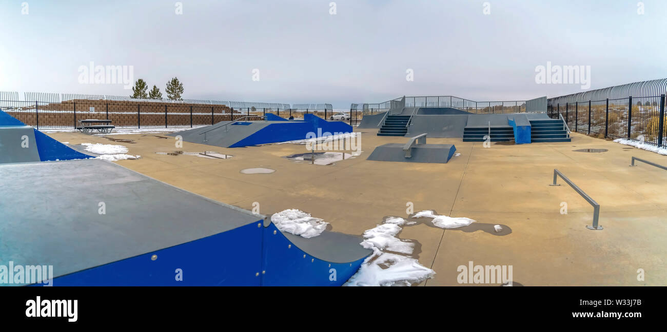 Skate park with various types of ramps under cloudy sky in winter ...