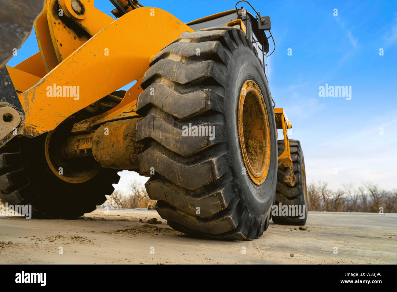 Close up view of the huge black rubber tires of a yellow construction ...