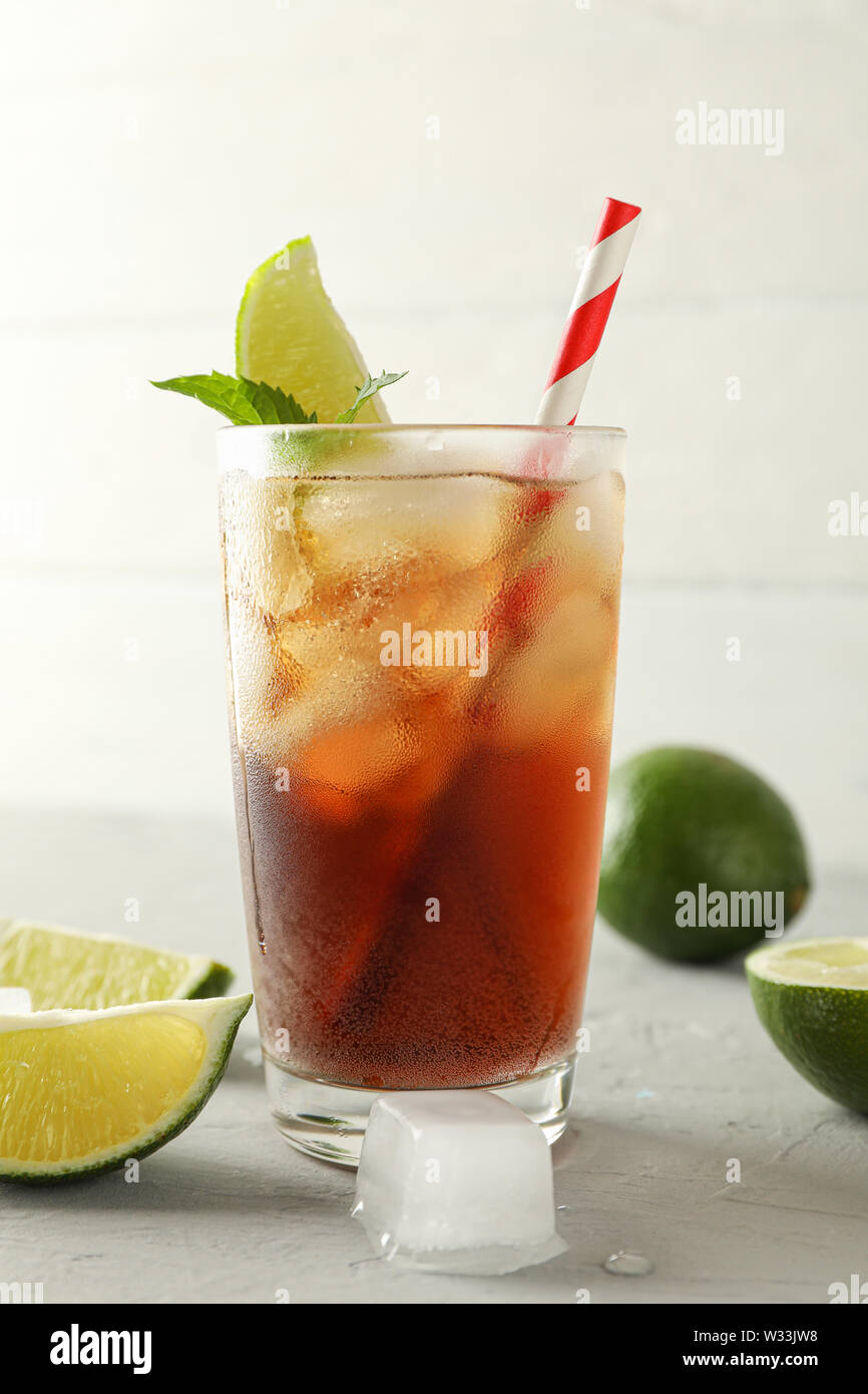 Glass with cold cola and citrus on grey cement background, space for ...