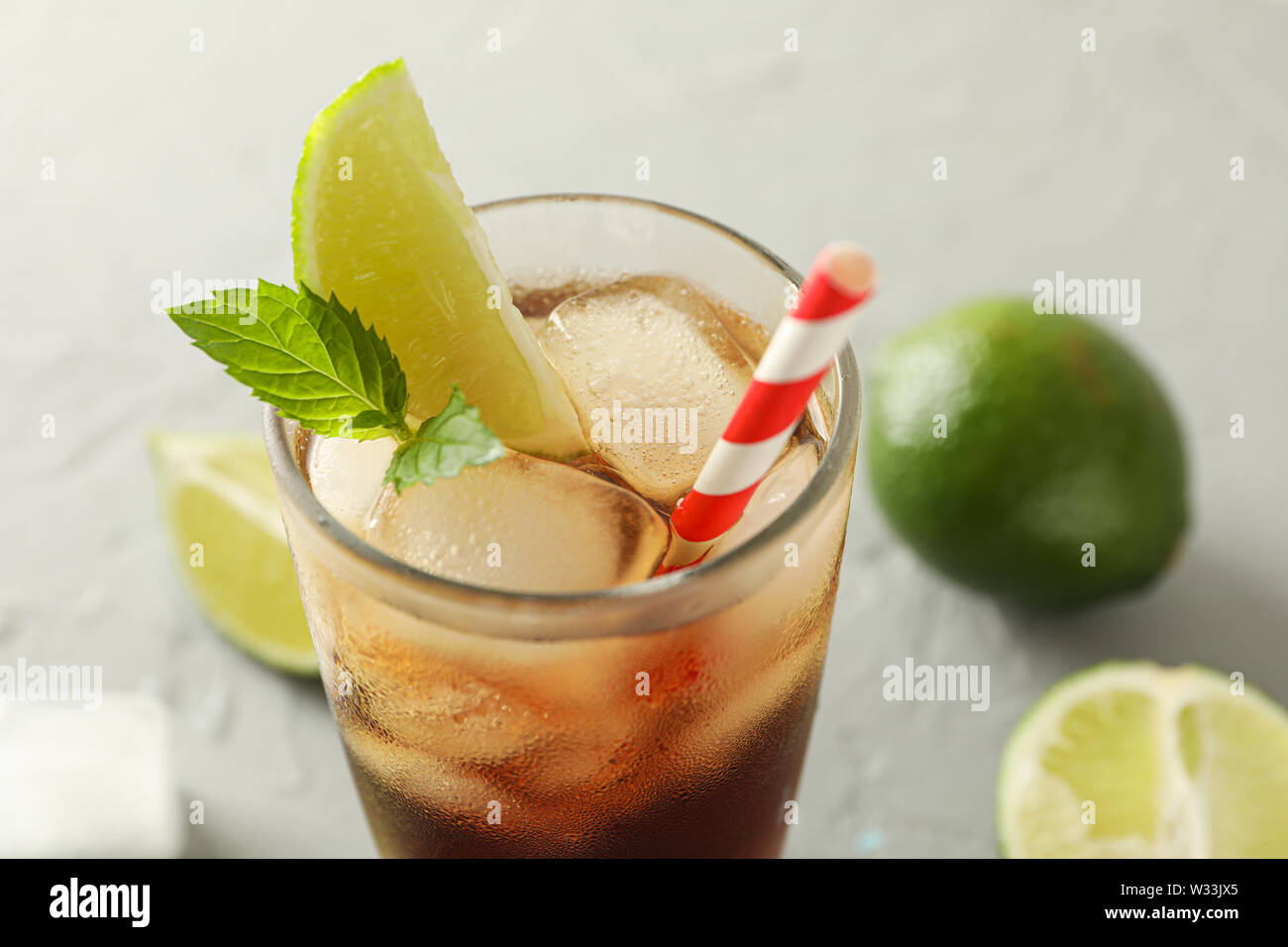 Glass with cold cola and citrus on grey cement background, space for ...