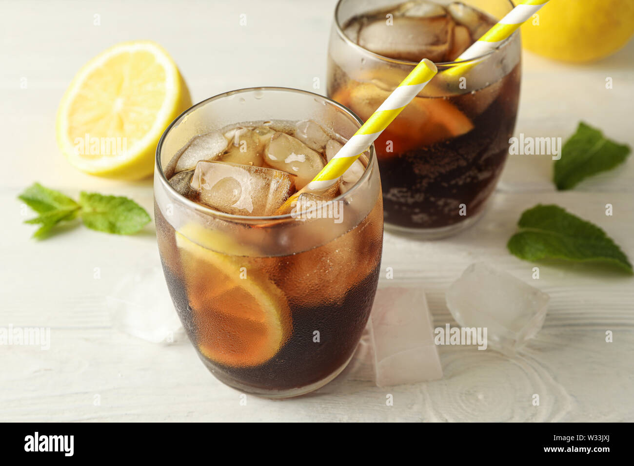 Glasses with cold cola and citrus on white cement background, closeup ...