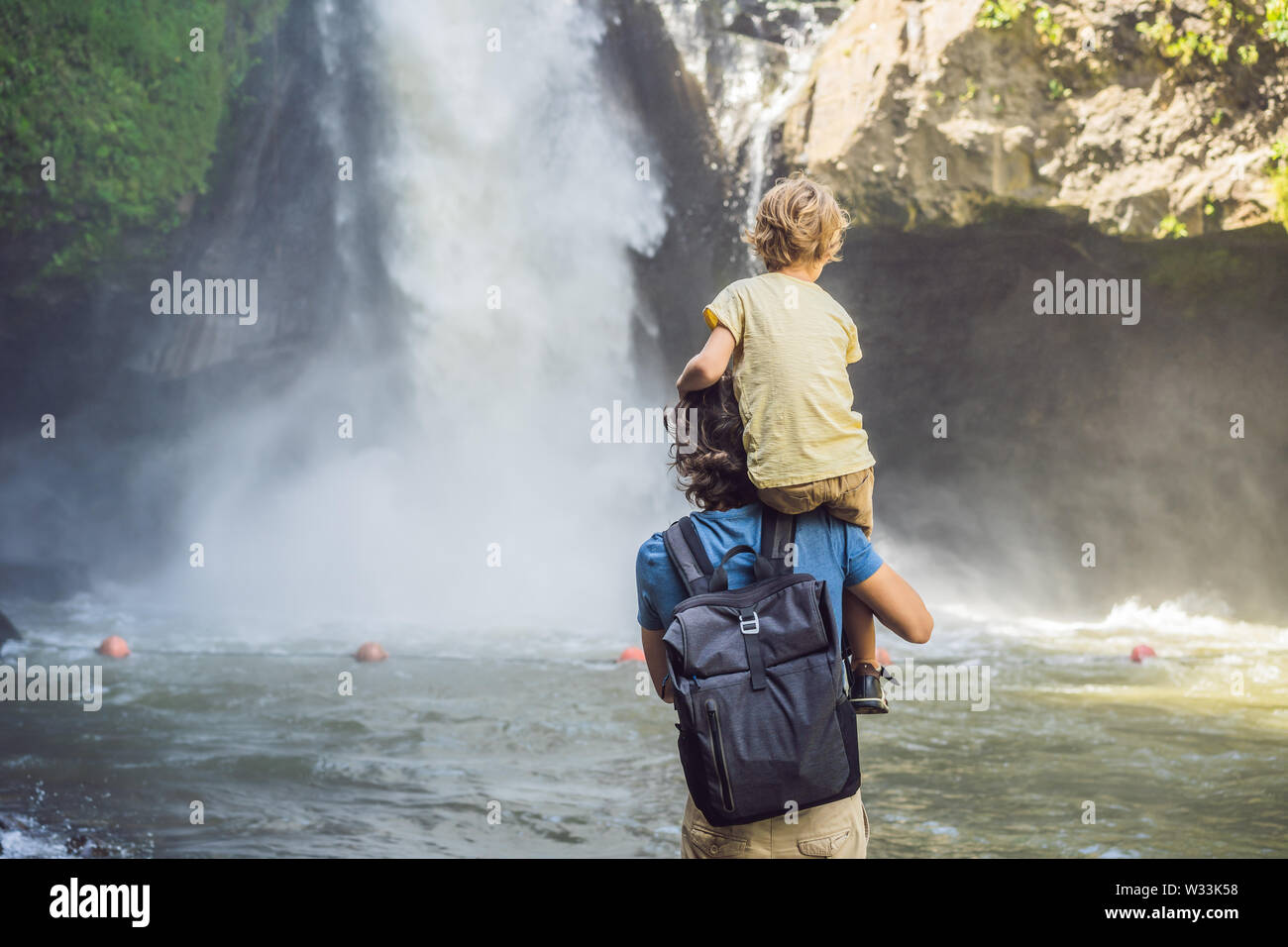 Dad and son tourists on the background of a waterfall. Traveling with ...