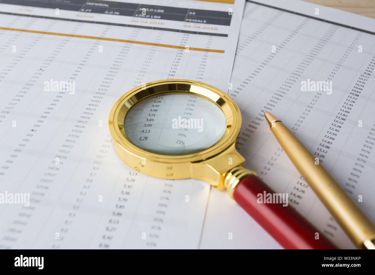 Looking through magnifying glass to financial report Stock Photo - Alamy
