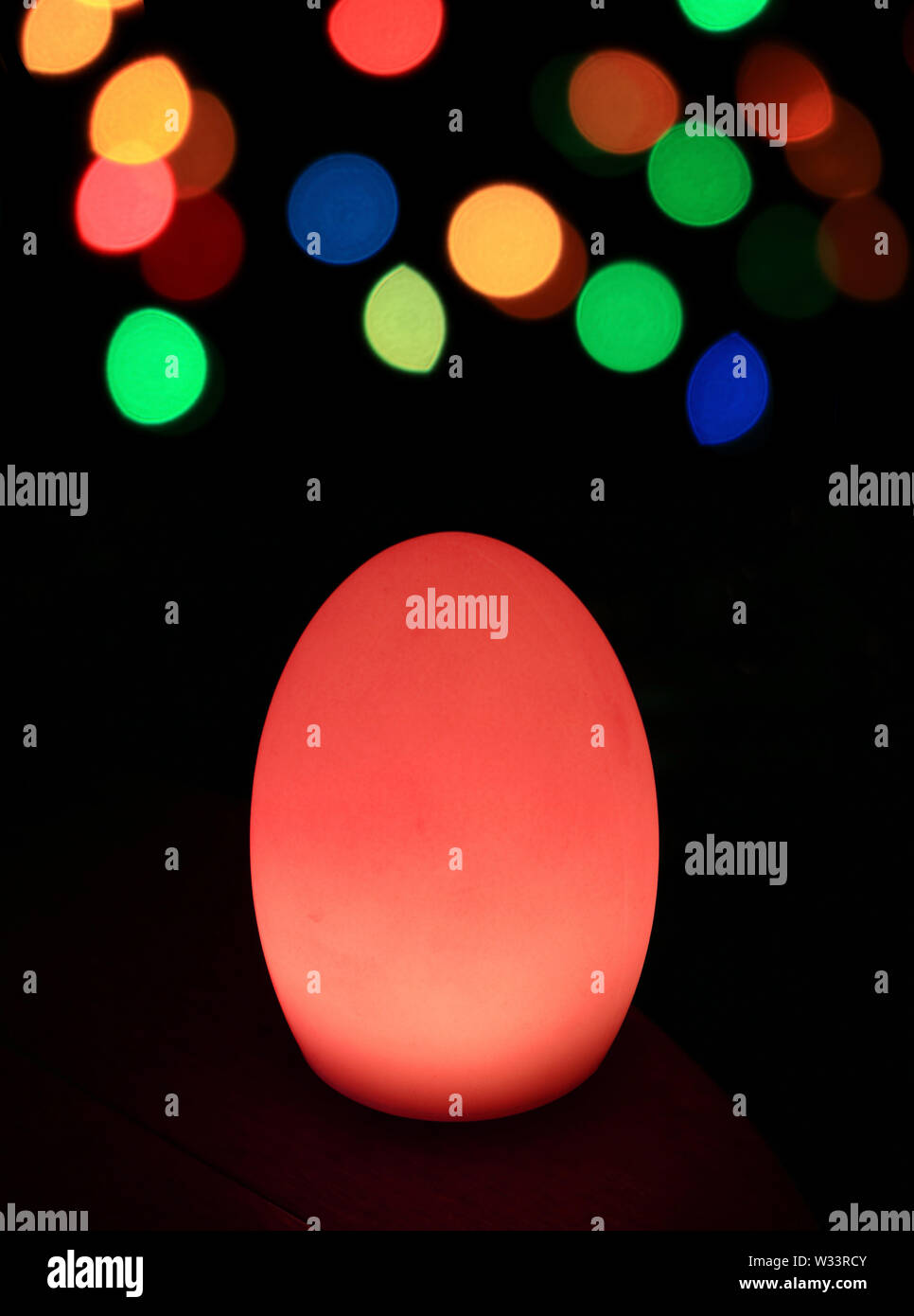 Vibrant red egg shaped table lighting with colorful bokeh in the dark ...