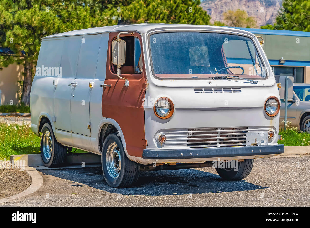 Front view of an old white van with brown door parked on concrete paved ...