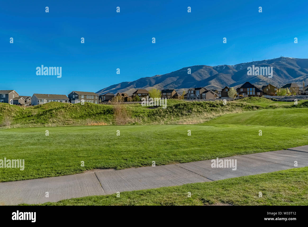 Narrow paved road on a vast grassy terrain covered with lush green ...