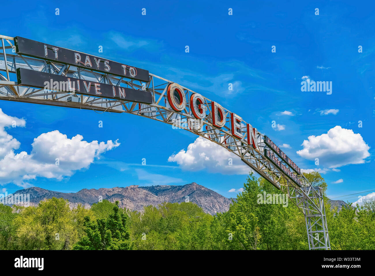 The welcome arch in Ogden Utah against vibrant trees and towering ...