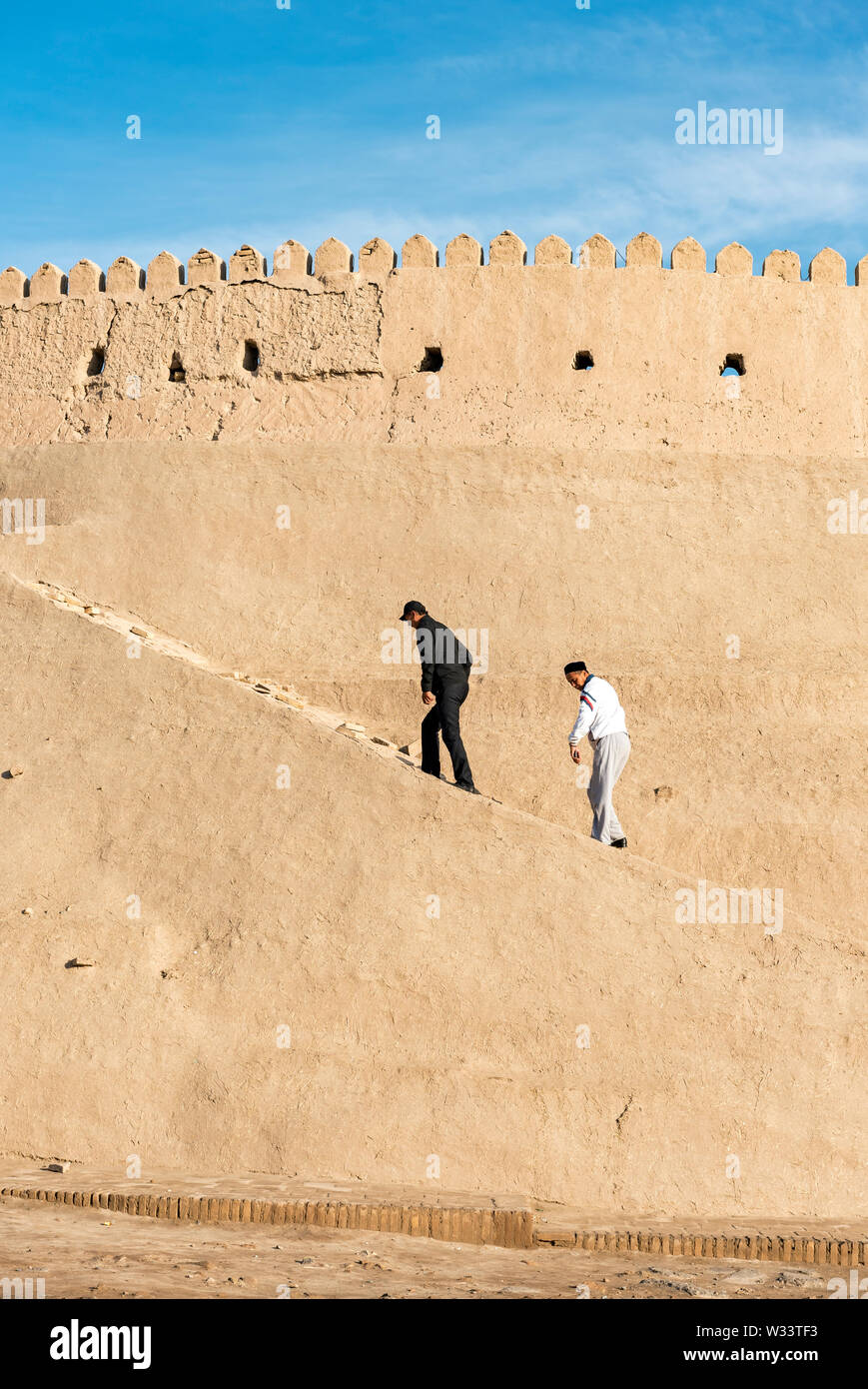 Two Uzbek men walk up the city walls of Khiva, Uzbekistan Stock Photo ...