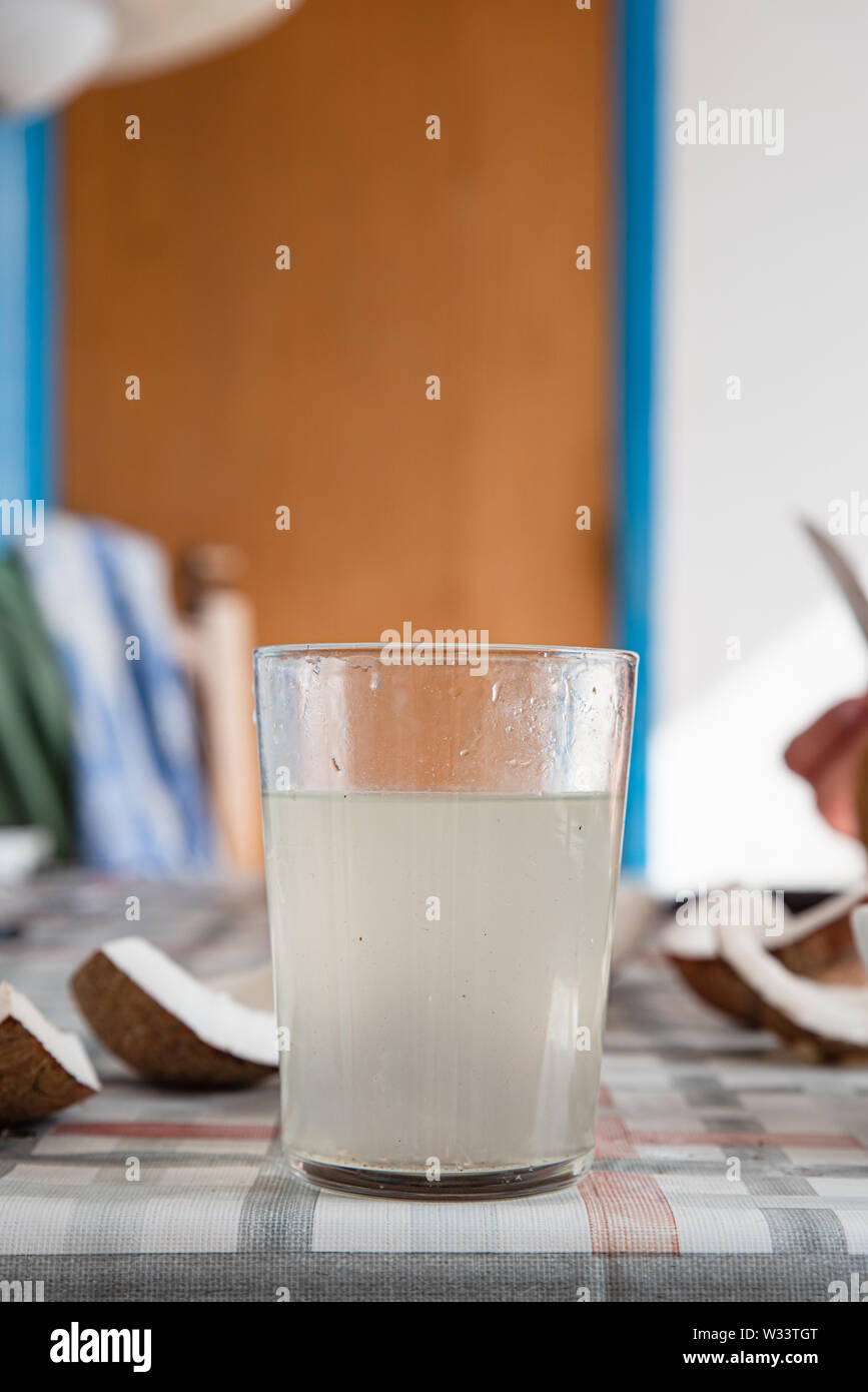 Coconut water and fresh pieces coconut on the table. Exotic food form ...